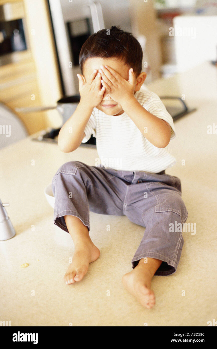 Boy with hands over eyes Stock Photo - Alamy
