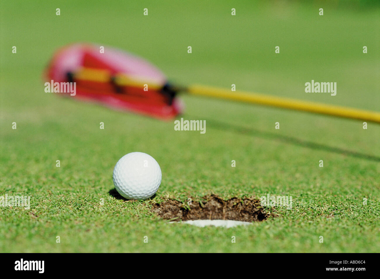 Golf ball next to hole Stock Photo - Alamy