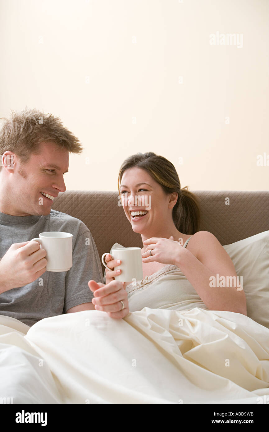 Happy couple having coffee in bed Stock Photo - Alamy