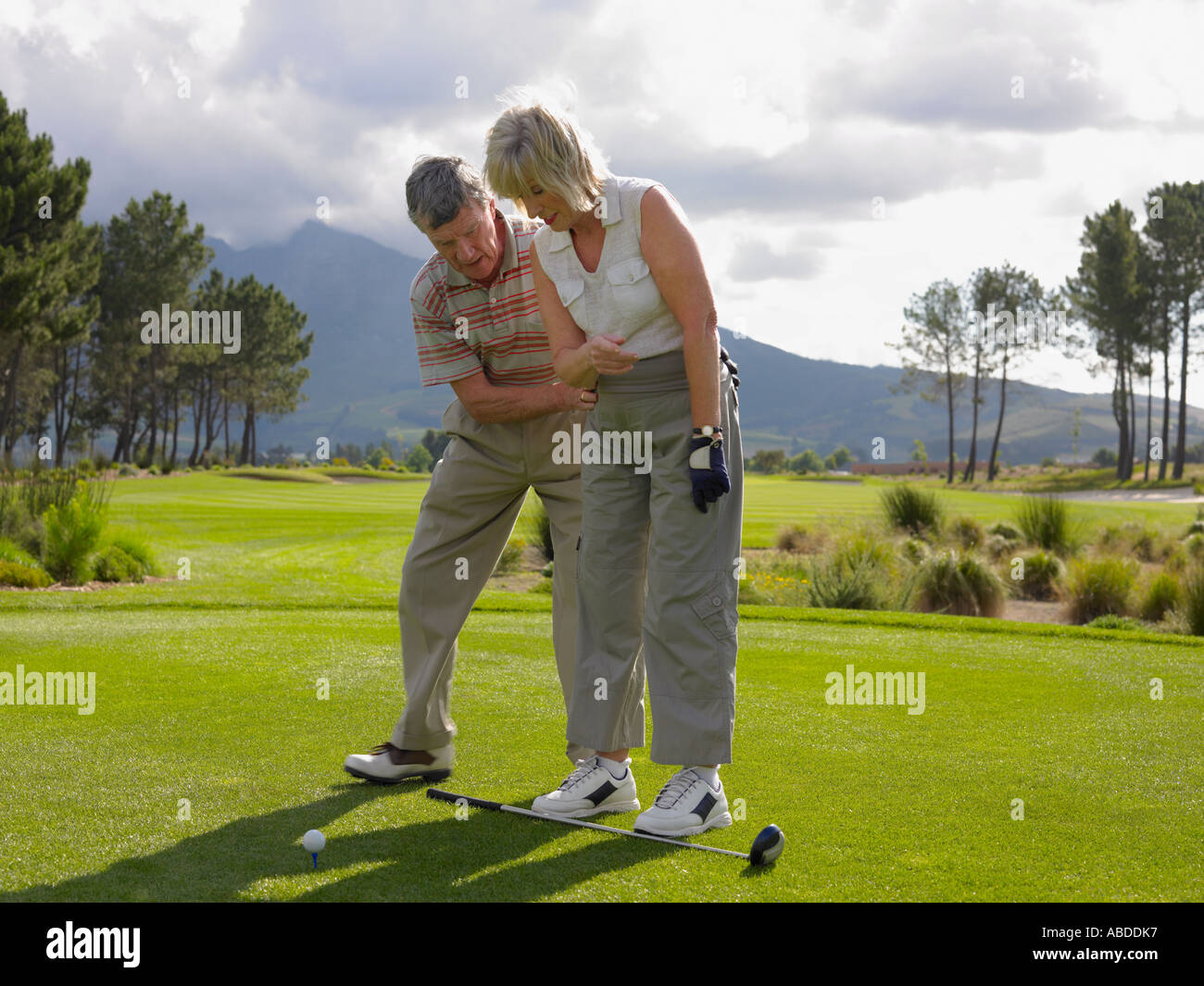 Man giving woman a golf lesson Stock Photo - Alamy