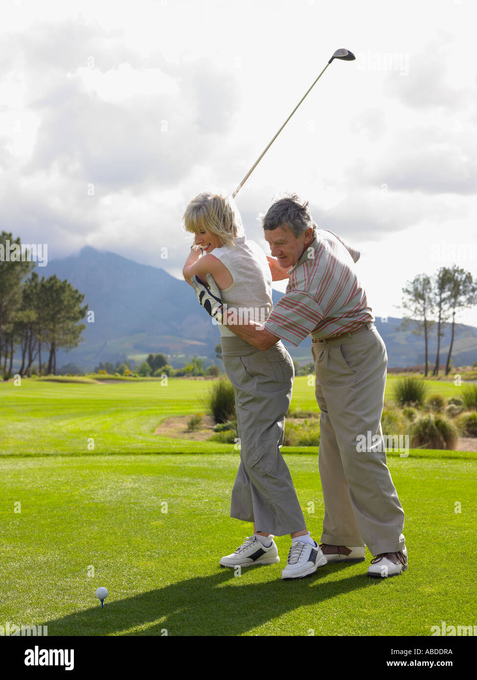 Man giving woman a golf lesson Stock Photo - Alamy