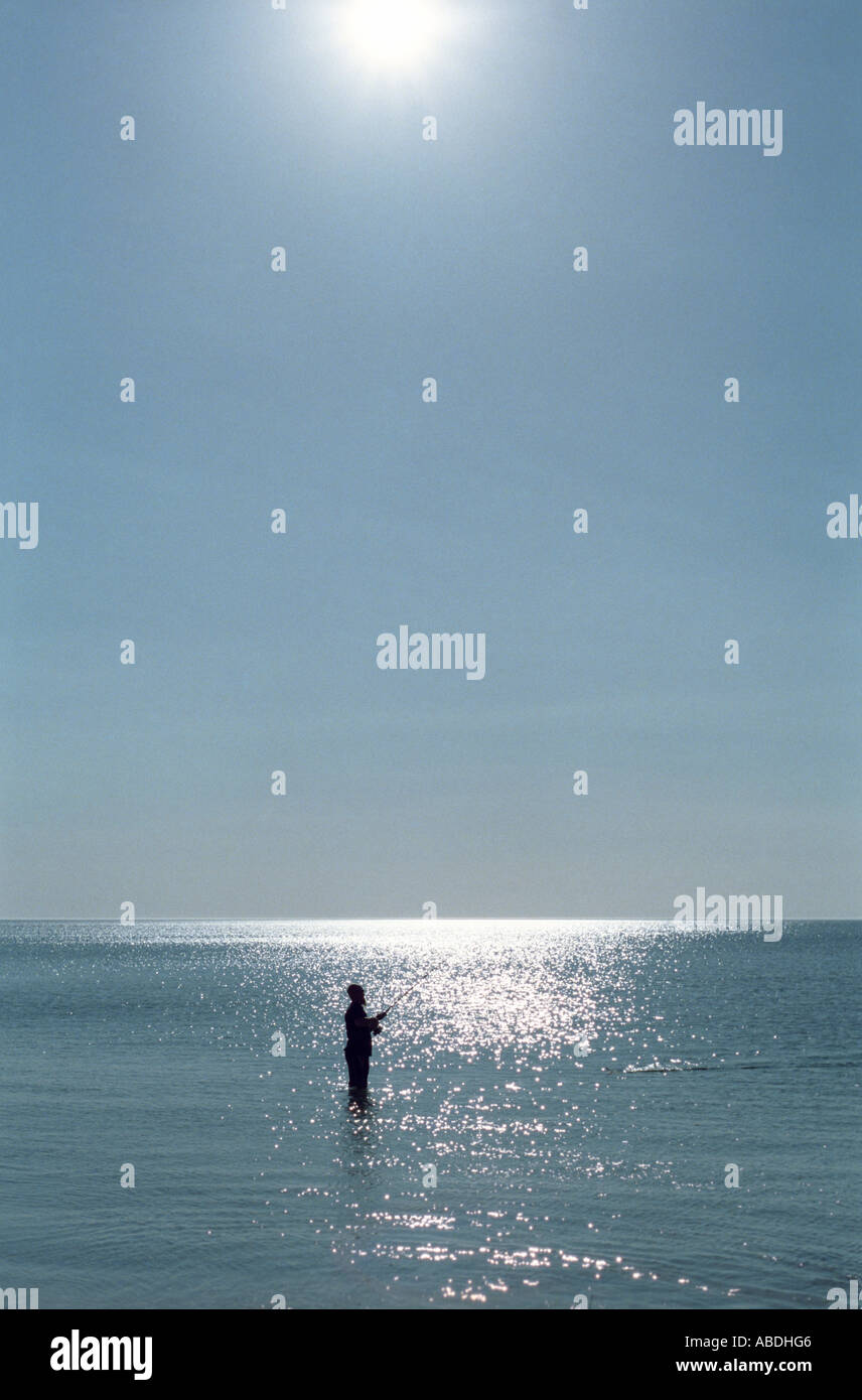 Cool looking angler standing knee deep in afternoon sea Stock Photo - Alamy