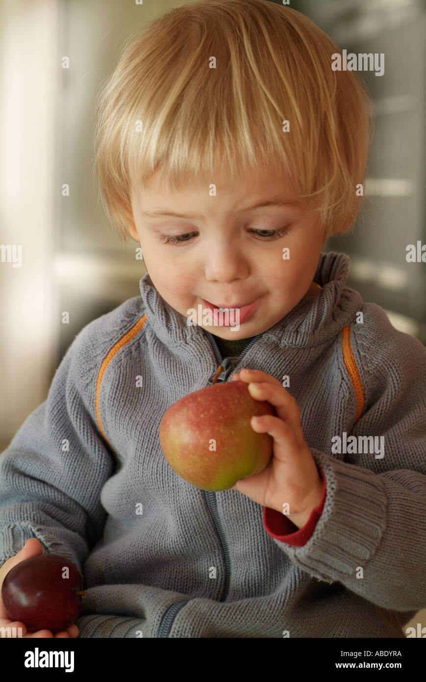 a young boy chooses between an apple and a plum Stock Photo - Alamy