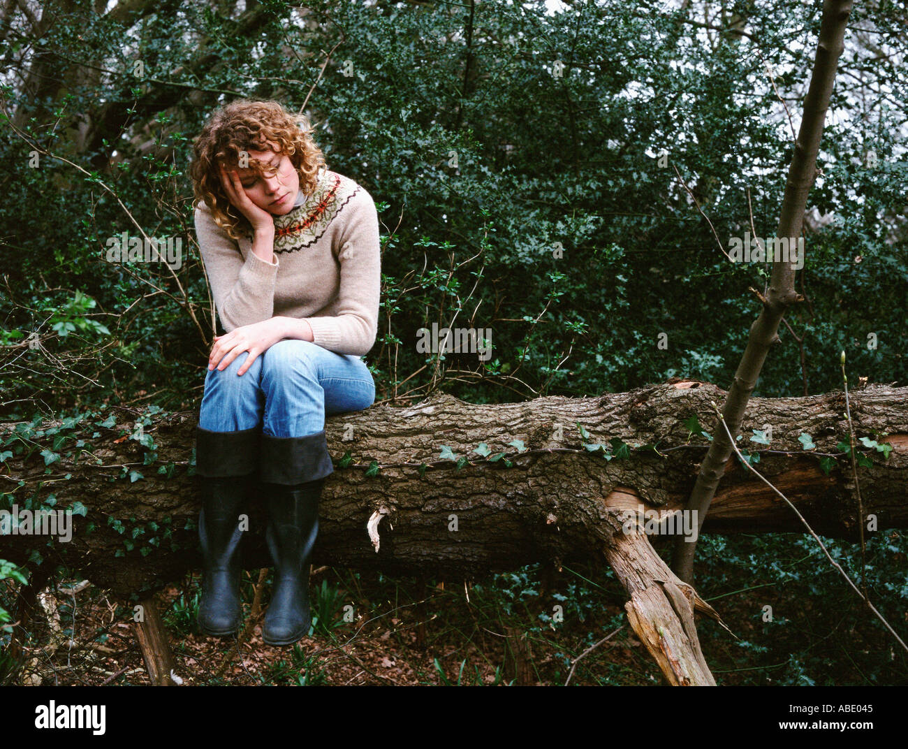 Woman sitting on a tree trunk Stock Photo - Alamy