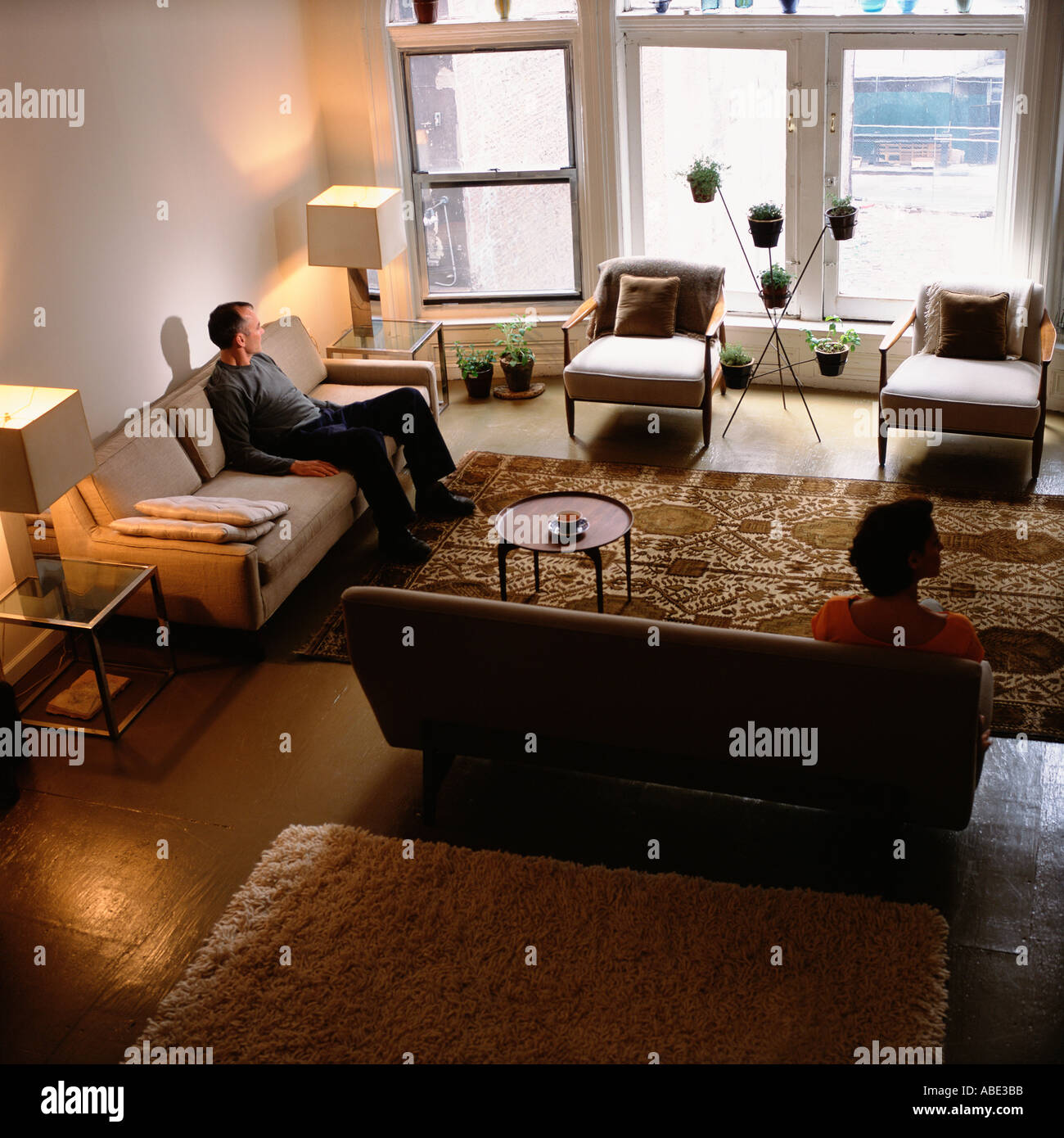 Couple sitting apart in living room Stock Photo - Alamy