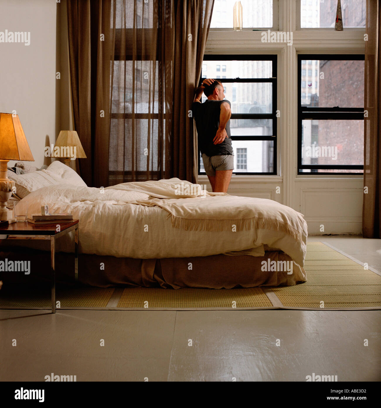 Man standing at window in bedroom Stock Photo - Alamy