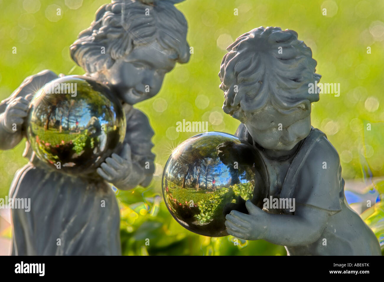 Statues of small children holding metal, reflective globes in a ...