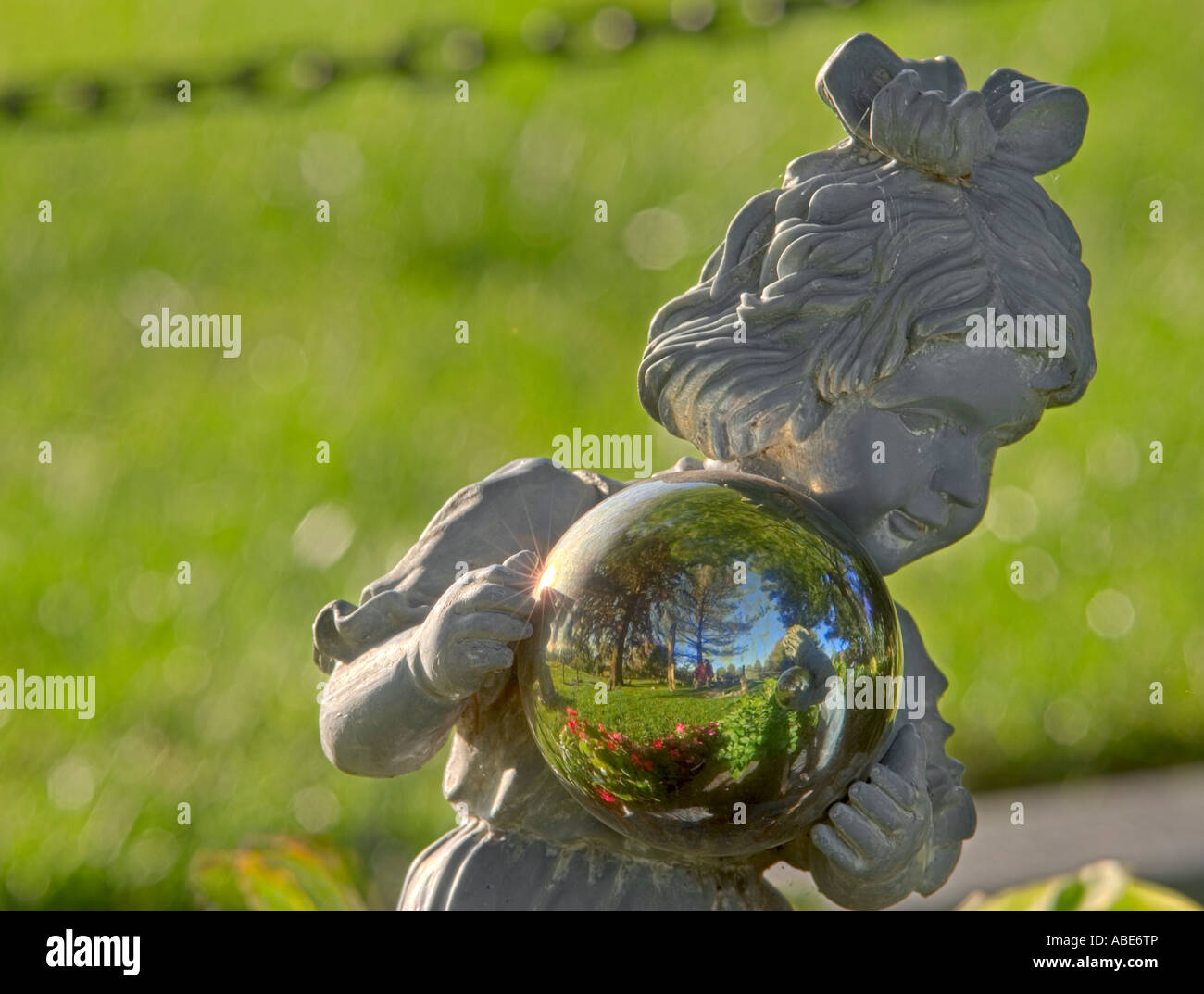 A statue of a small child holding a metal, reflective globe in a ...