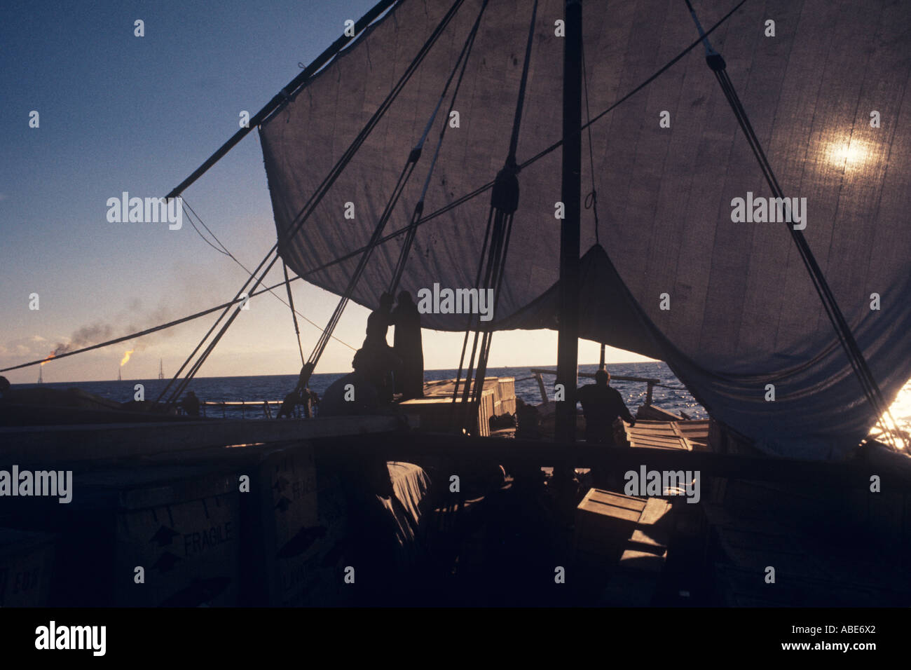 In the Persian Gulf morning sun shines through a small dhow's lateen ...