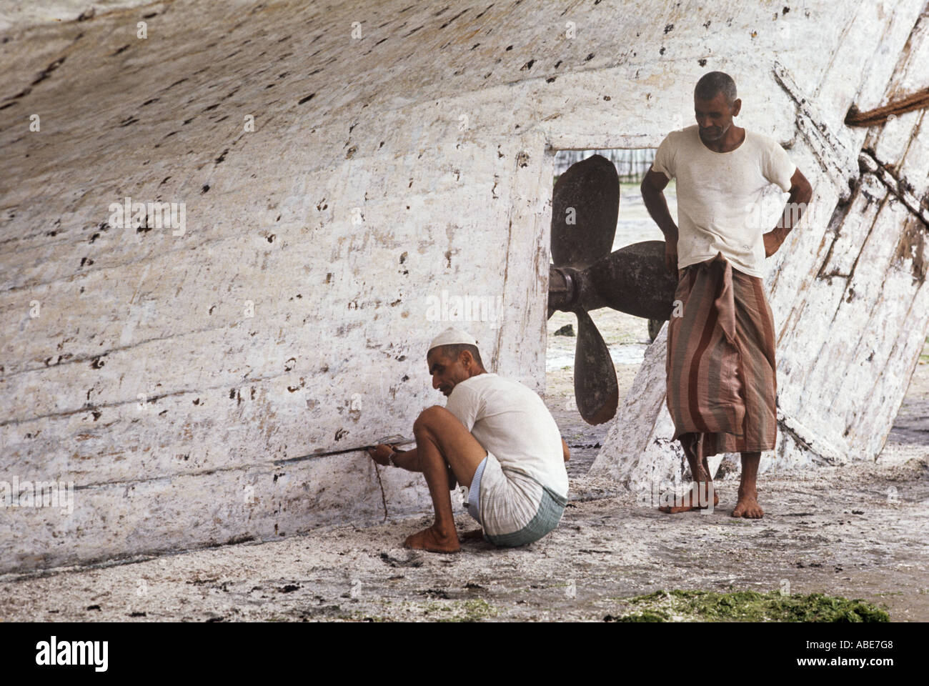 A dhow's nakhoda, or shipmaster, caulks the hull of his dhow where ...