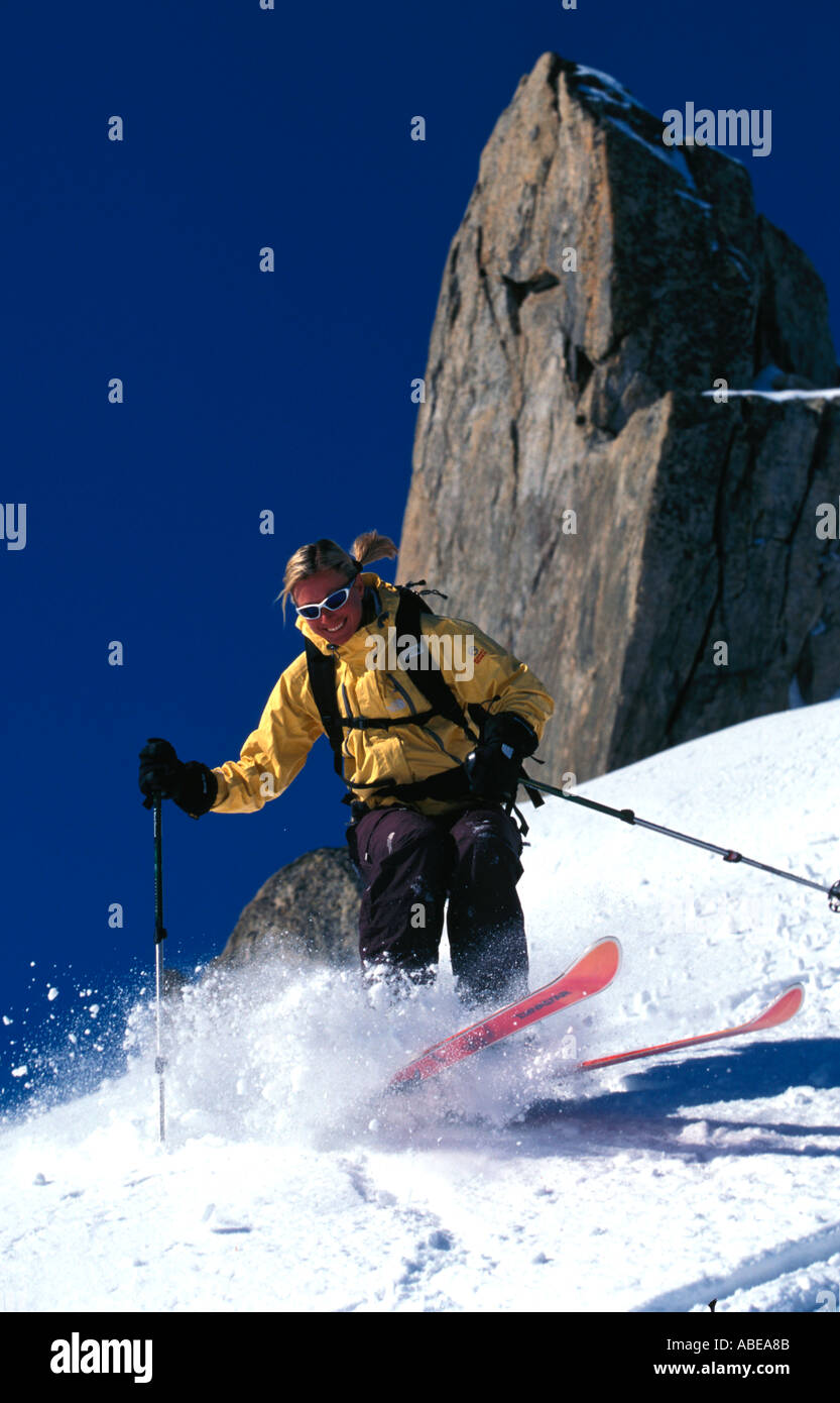 Skiing down a steep slope with a rock face behind Stock Photo - Alamy