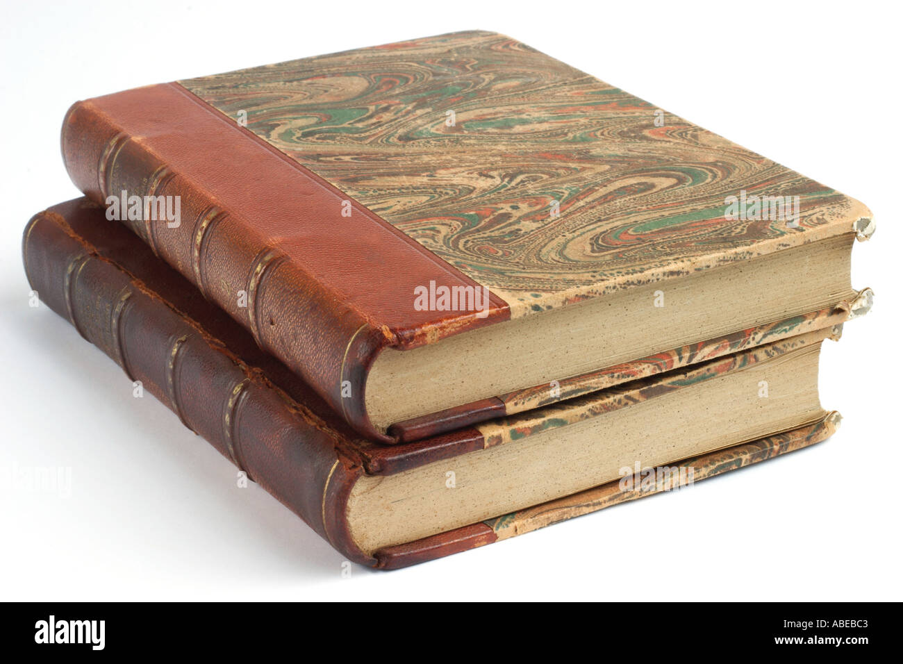 Two old worn antique leather and marbled paper books stacked on a white ...