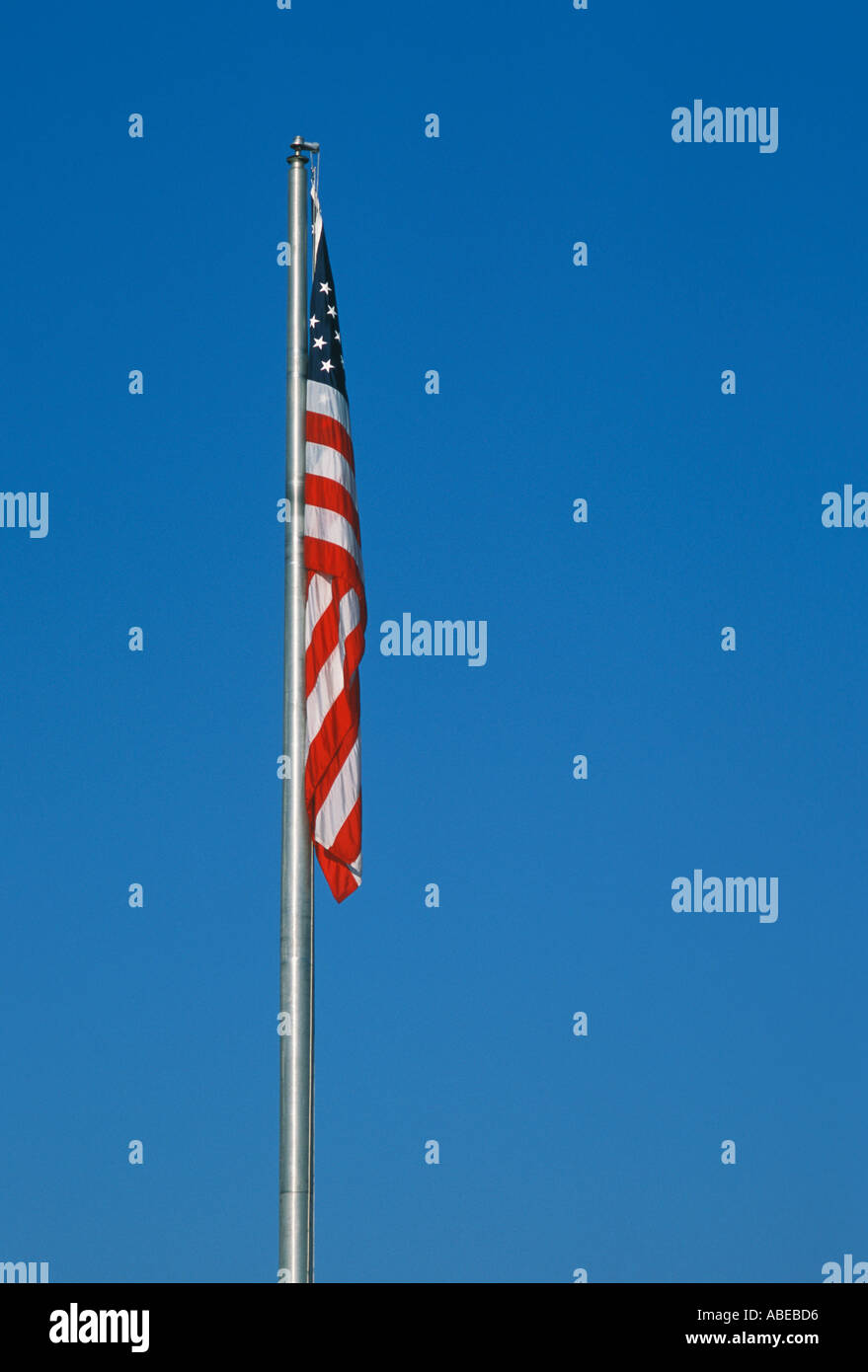 A furled American flag hanging motionlessly on it s staff and with a ...