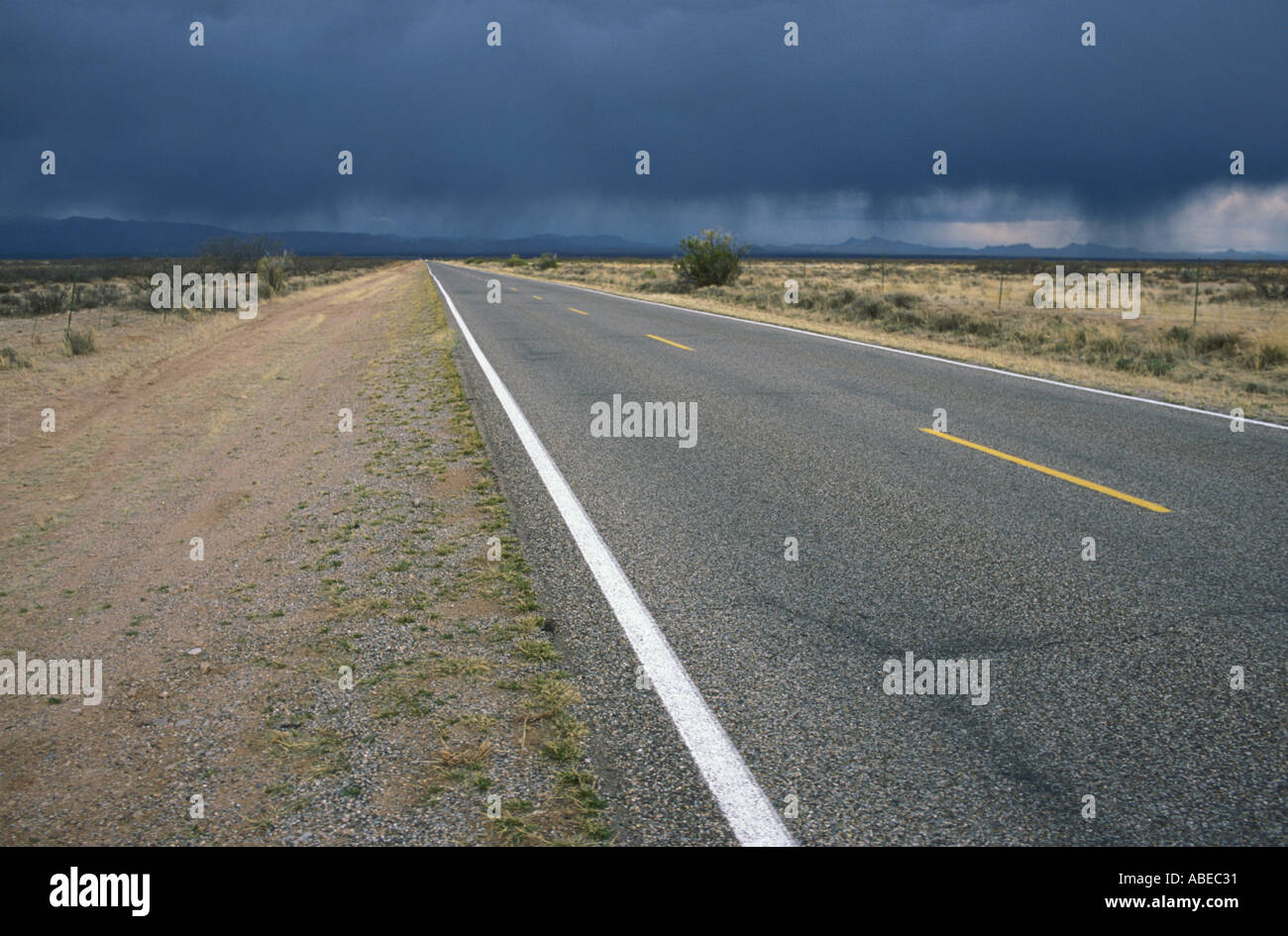 Roadside view of a bare stretch of paved highway receding into in a dry ...