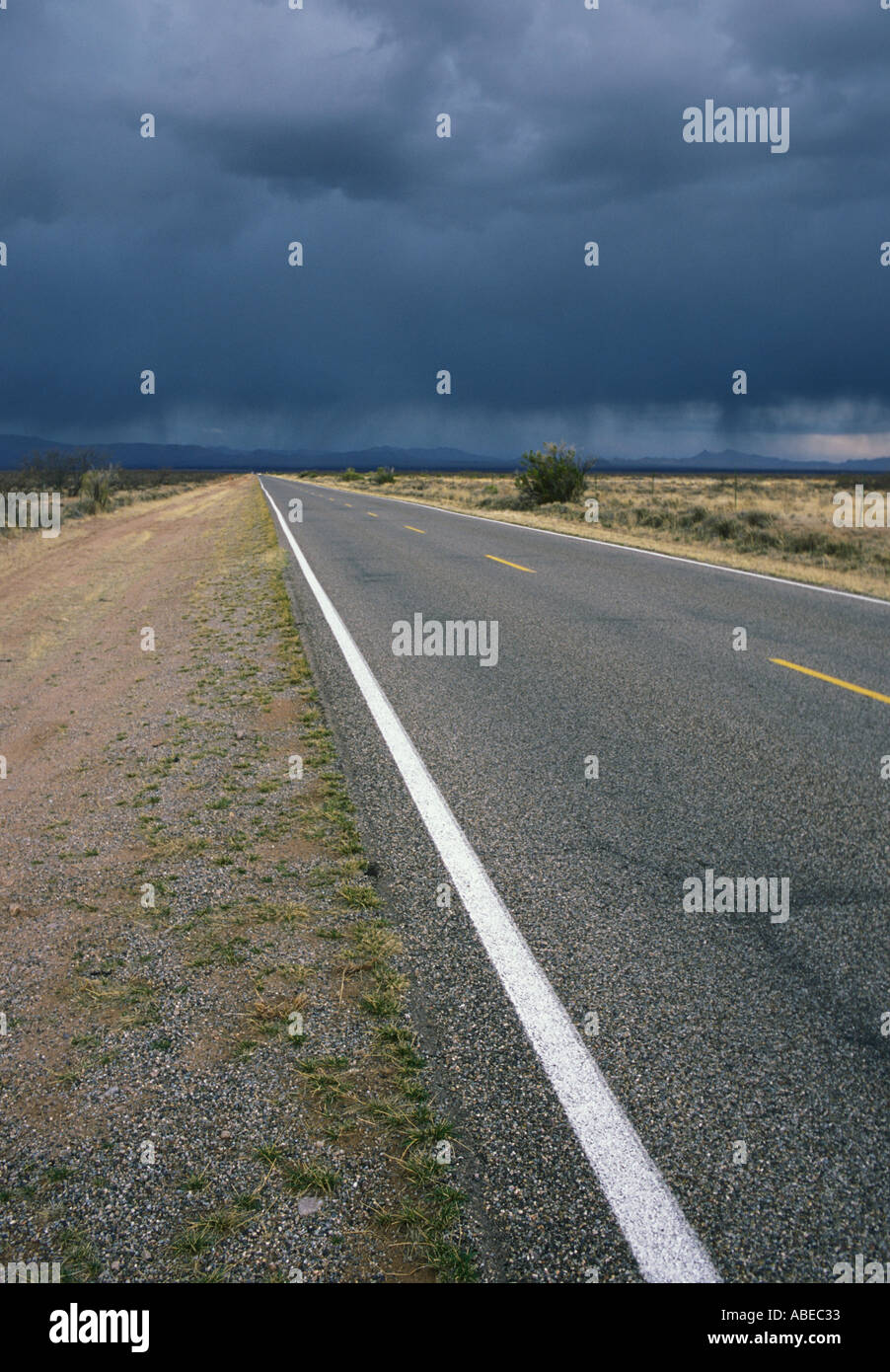 Roadside view of a bare stretch of paved highway receding into in a dry ...