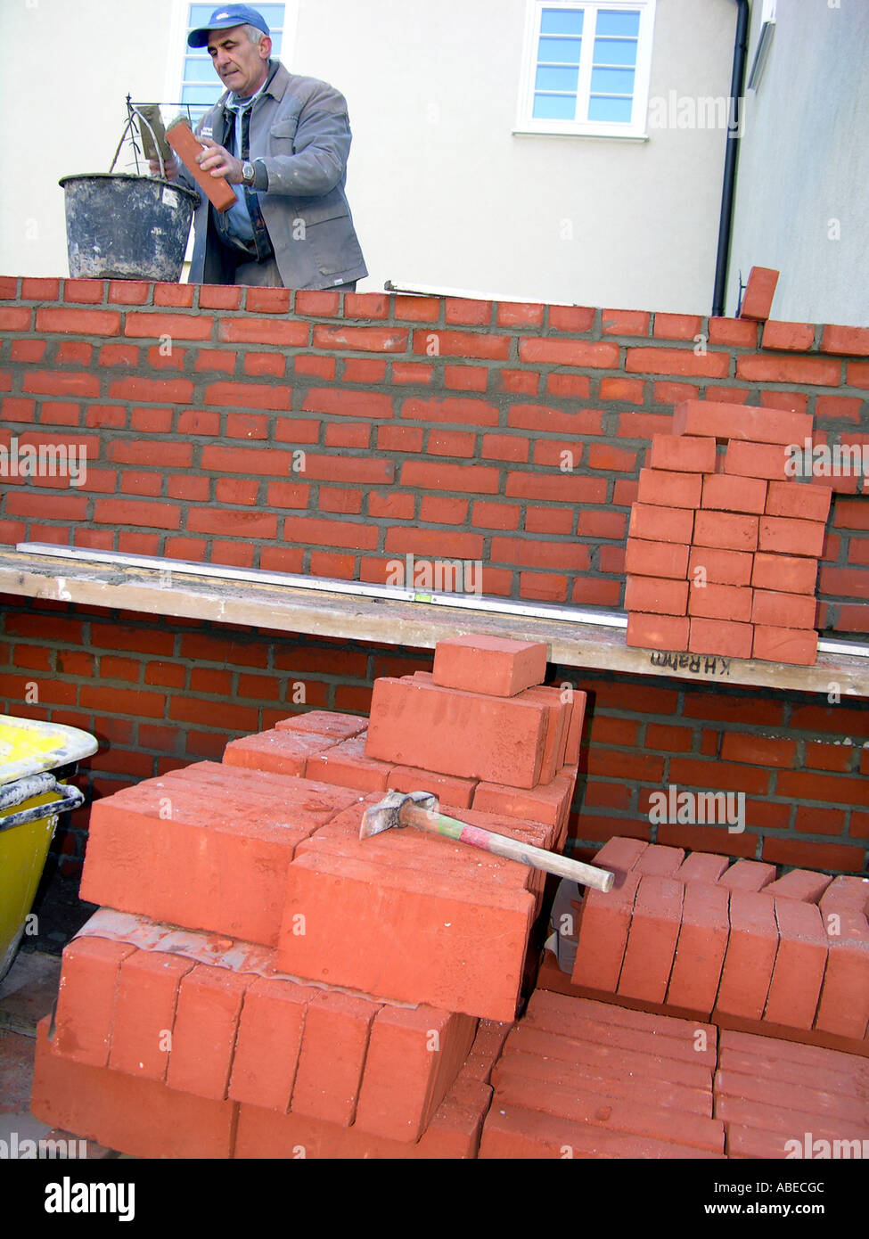 Building worker raising a brick wall Stock Photo - Alamy