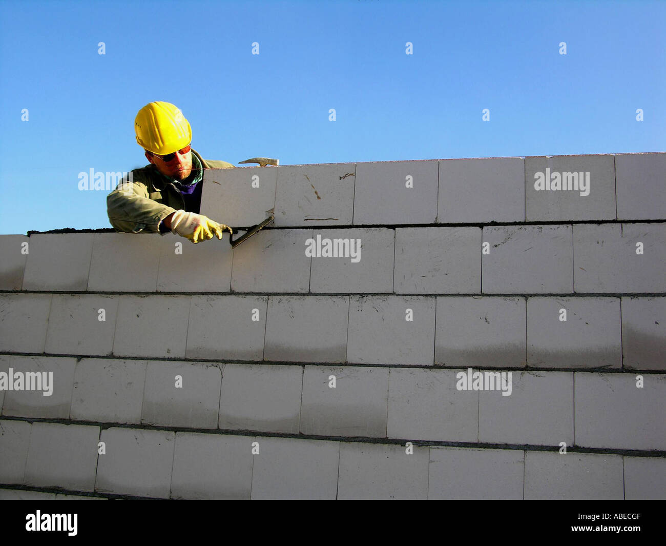 Building worker raising a brick wall Stock Photo - Alamy