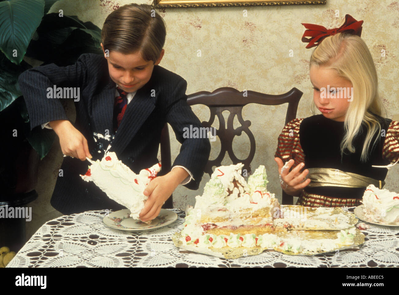 Two children dressed in nice clothing eating cake Stock Photo - Alamy
