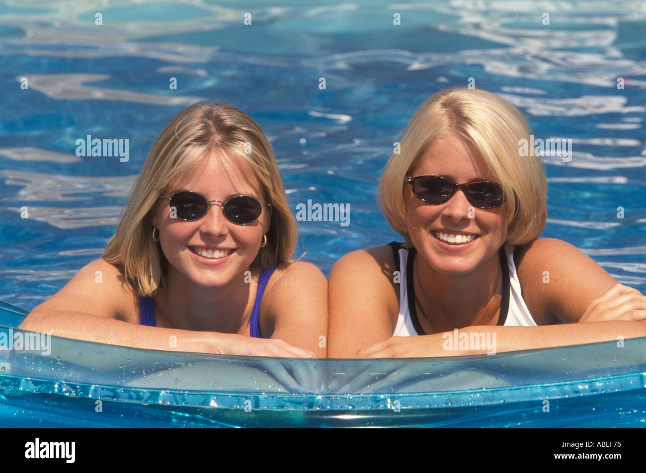 Two pretty young women relaxing on a raft in the pool Stock Photo - Alamy