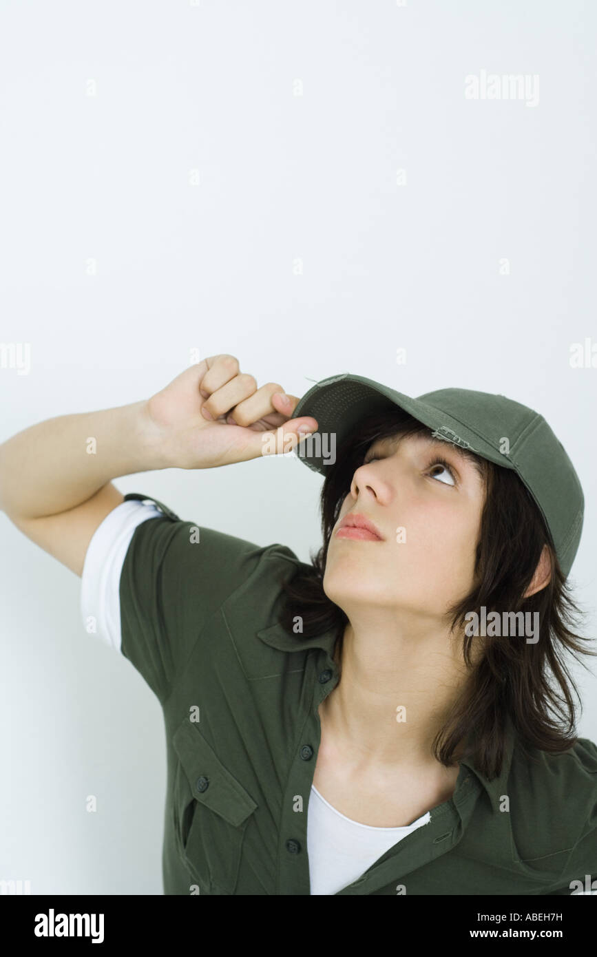 Teenage boy adjusting cap, looking up Stock Photo - Alamy