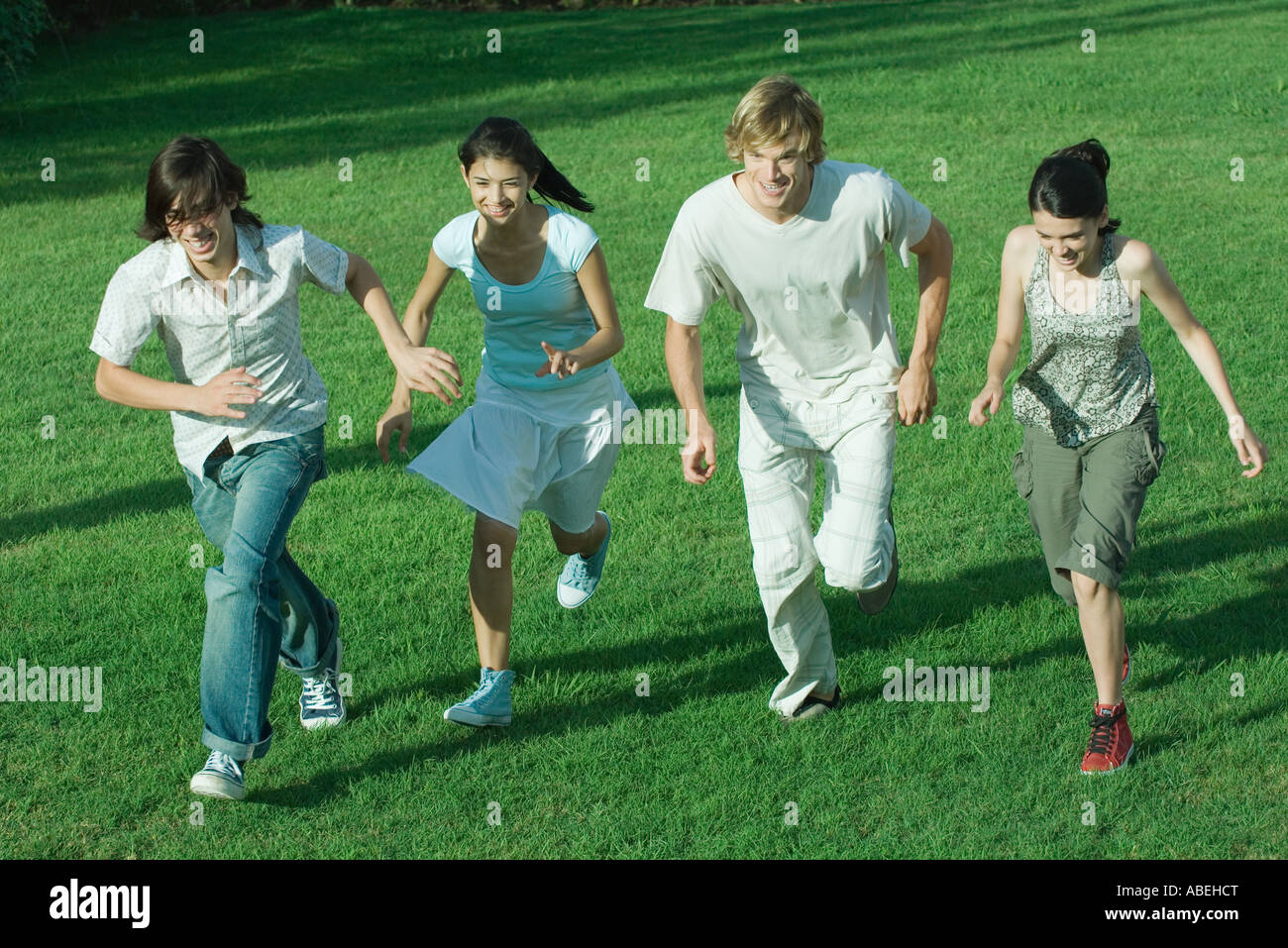 Group of young friends, running across grass together Stock Photo - Alamy