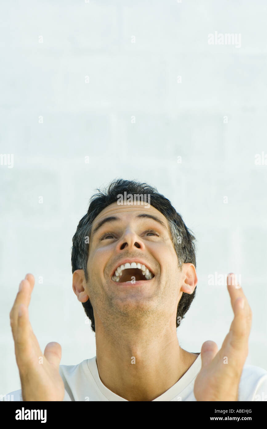 Man, head back and mouth wide open, holding up hands, head and ...