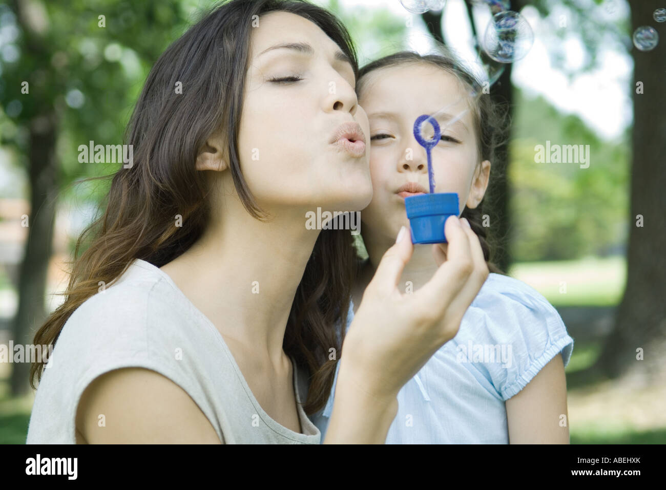 Girl and mother blowing bubbles together Stock Photo - Alamy