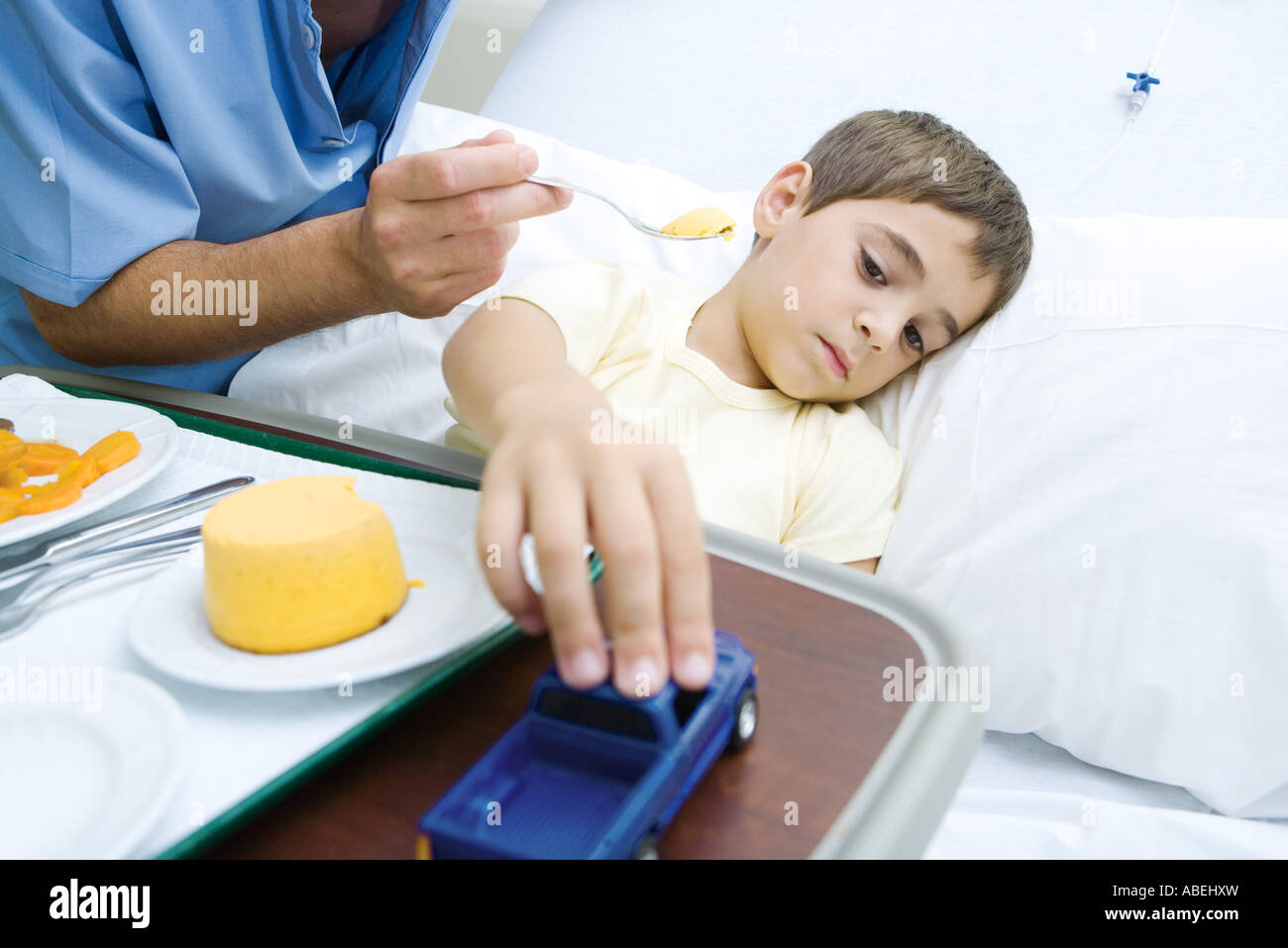 Intern feeding boy in hospital bed Stock Photo - Alamy