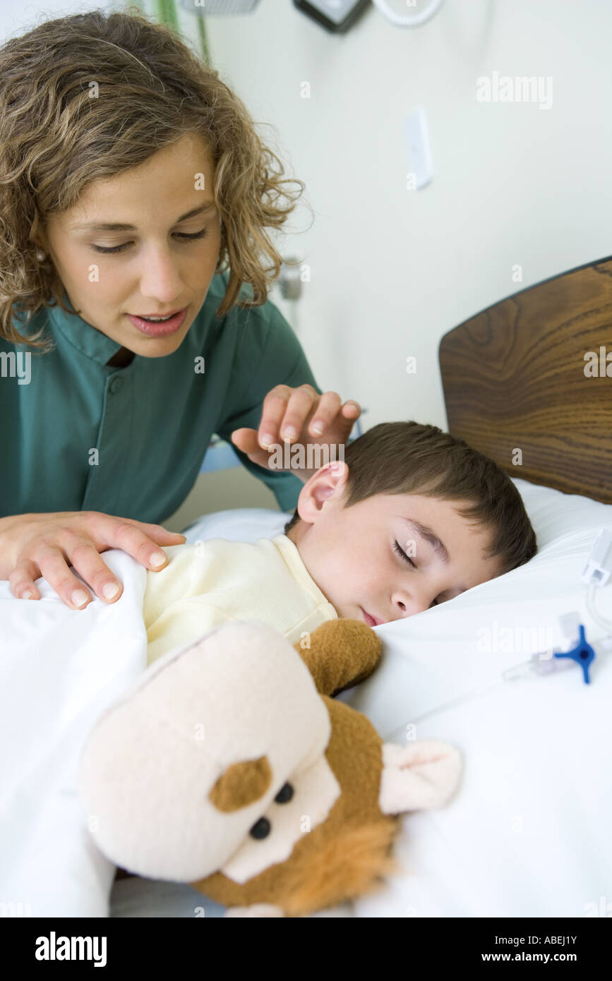 Boy sleeping in hospital bed, intern looking over boy's shoulder Stock ...