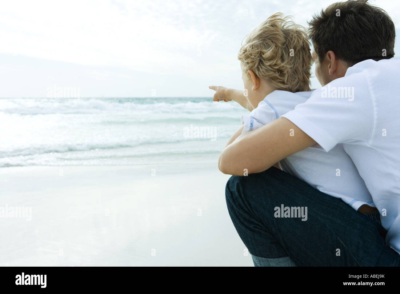 Man looking at ocean with son, rear view Stock Photo - Alamy