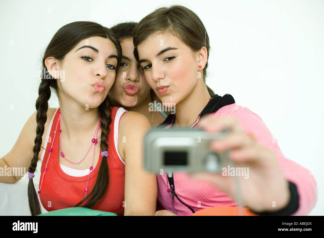 Three young female friends puckering as one takes photo with digital ...