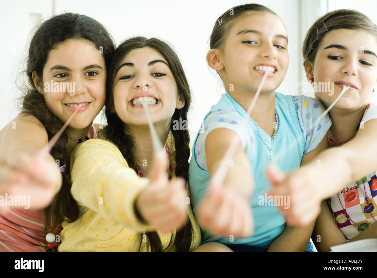 Four young female friends pulling chewing gum out of mouths Stock Photo ...
