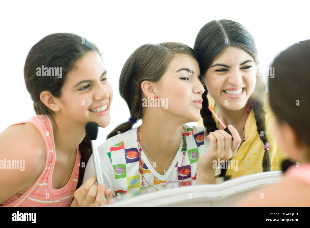 Three young female friends putting on make-up Stock Photo - Alamy