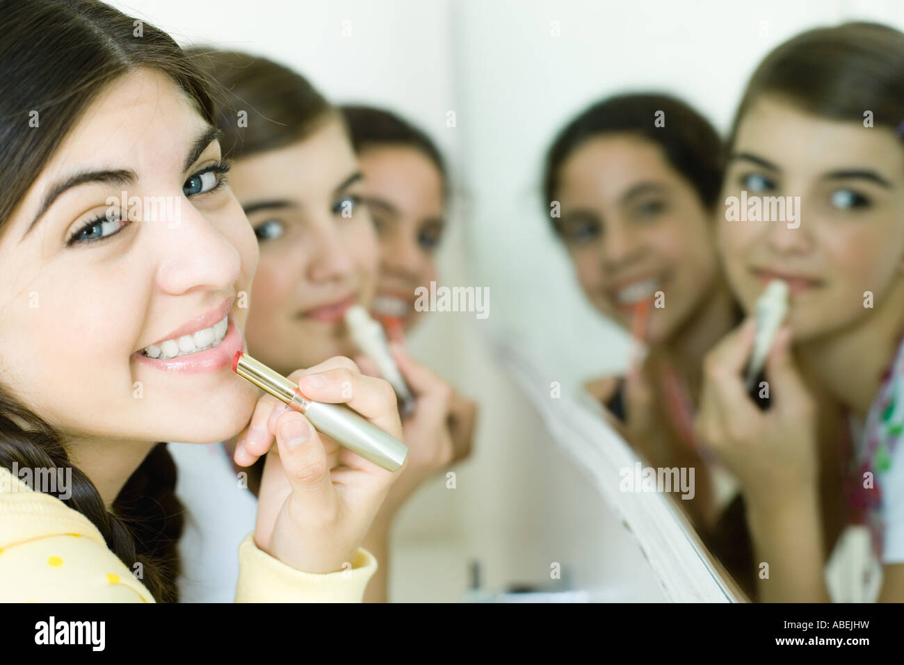 Three young female friends putting on make-up, smiling at camera Stock ...