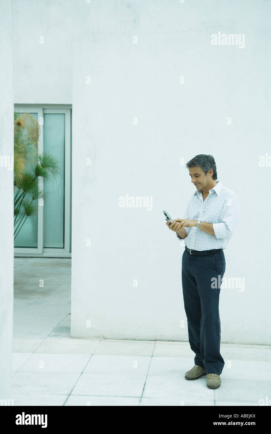 Man standing looking at cell phone, full length Stock Photo - Alamy