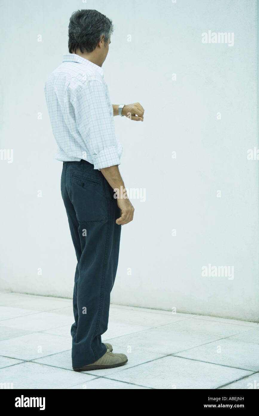 Man checking time on watch, full length Stock Photo - Alamy