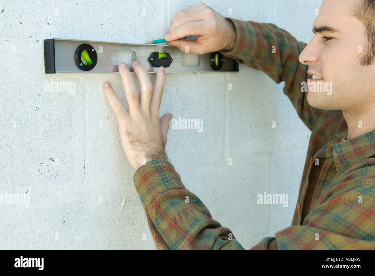 Man using level to draw line on wall Stock Photo - Alamy
