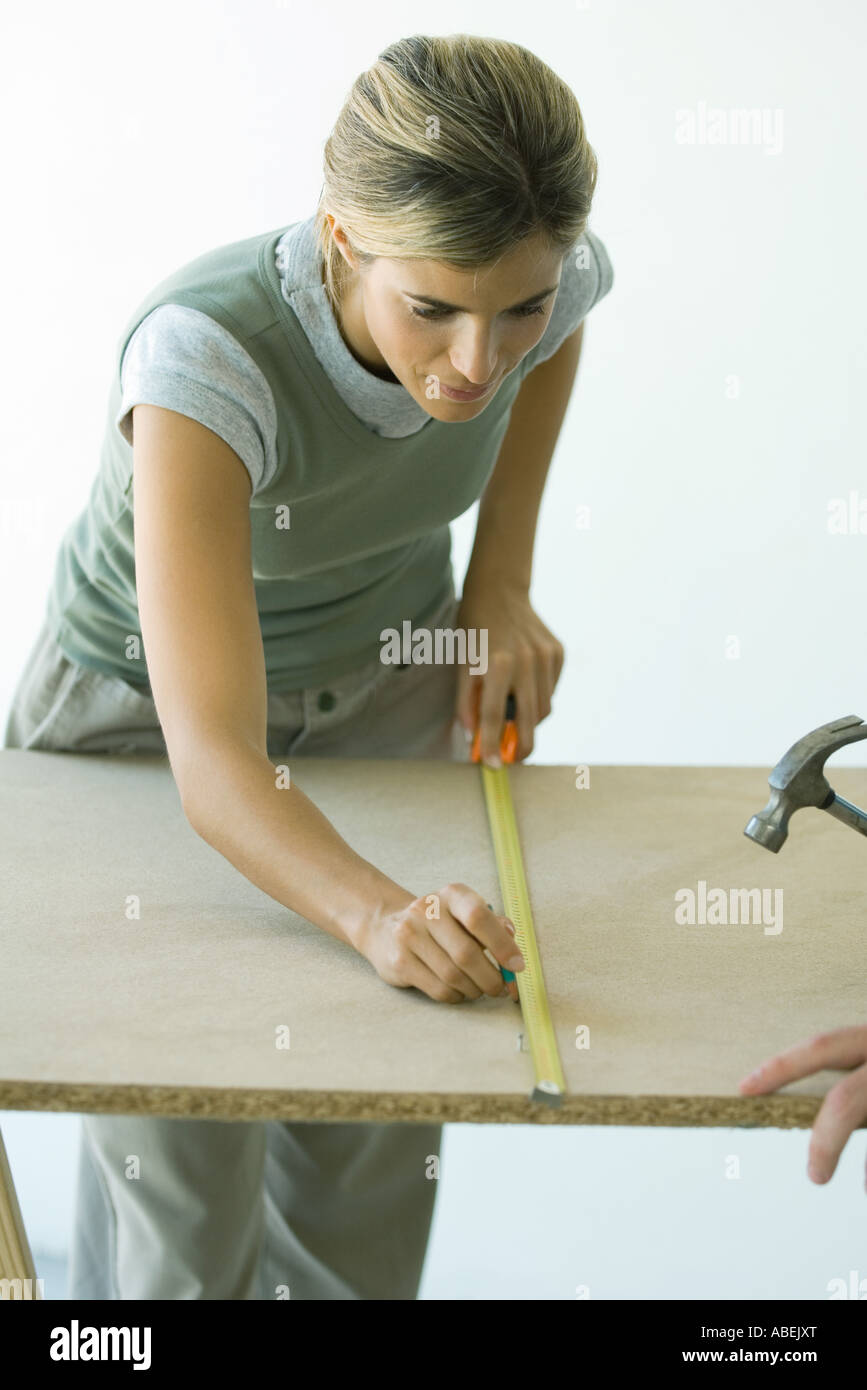 Woman using measuring tape to draw line on wood board Stock Photo - Alamy