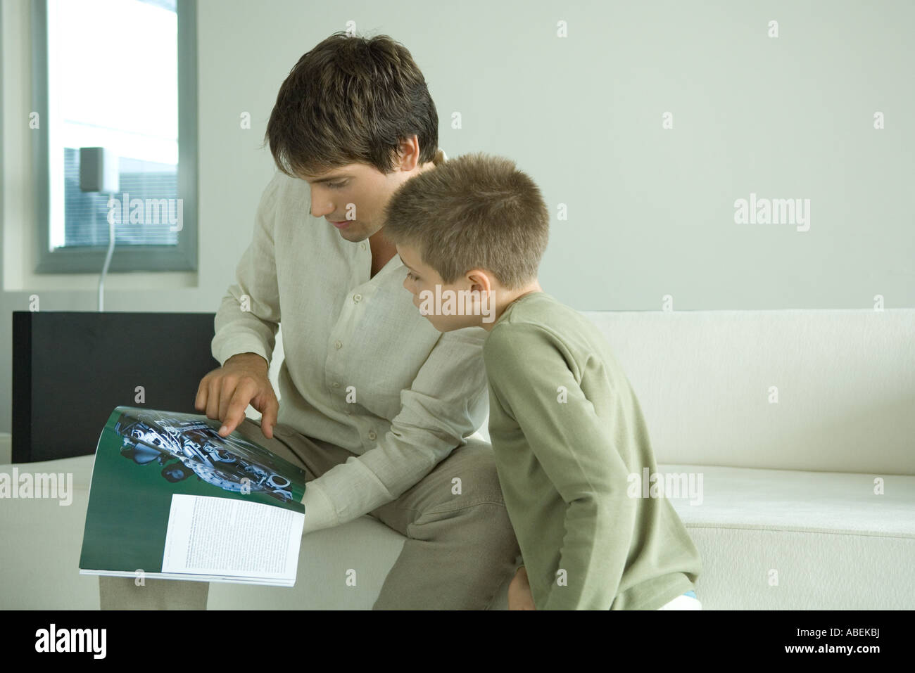 Father and son looking at magazine together Stock Photo - Alamy