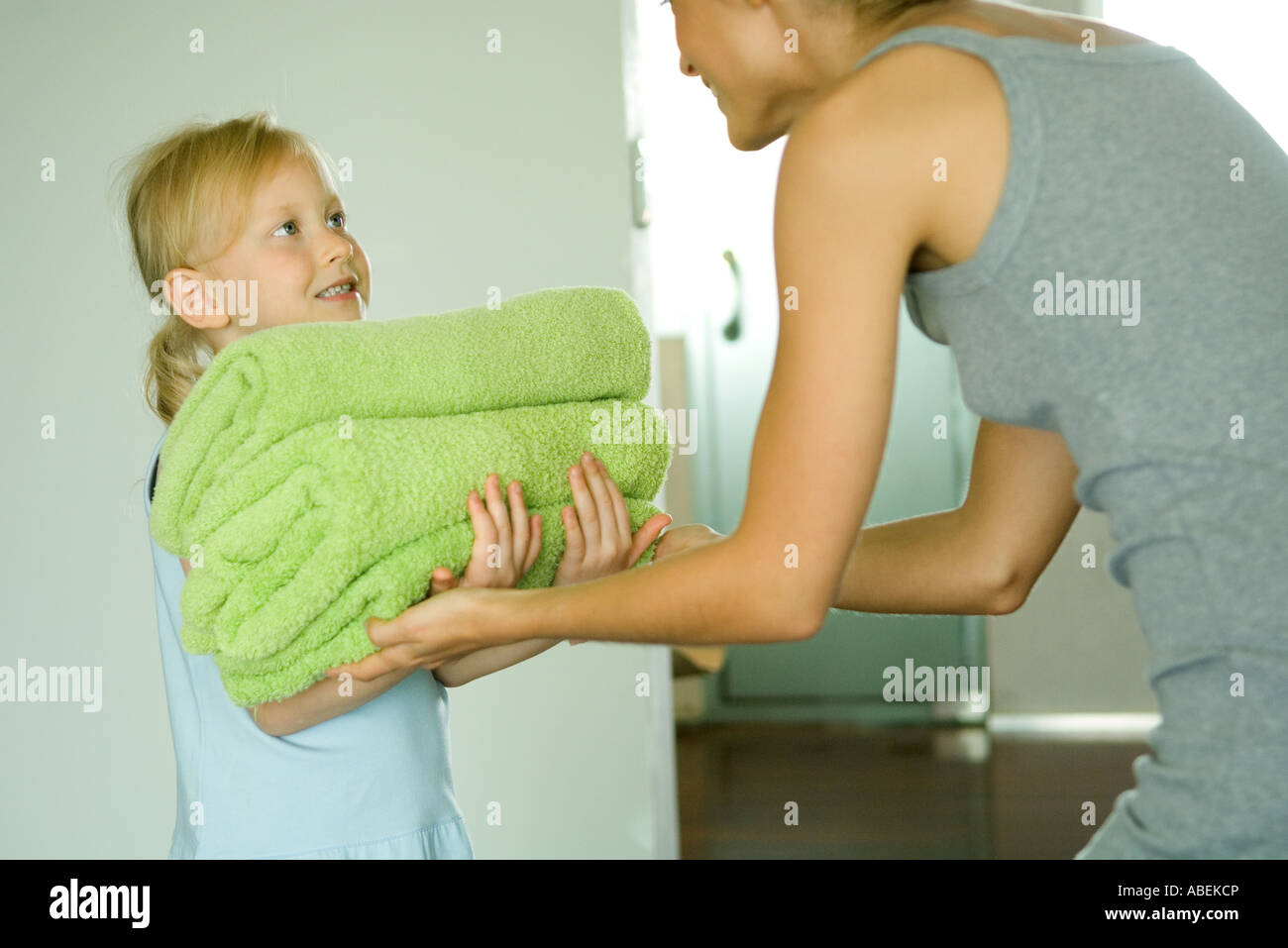 Girl handing mother stack of folded towels Stock Photo - Alamy