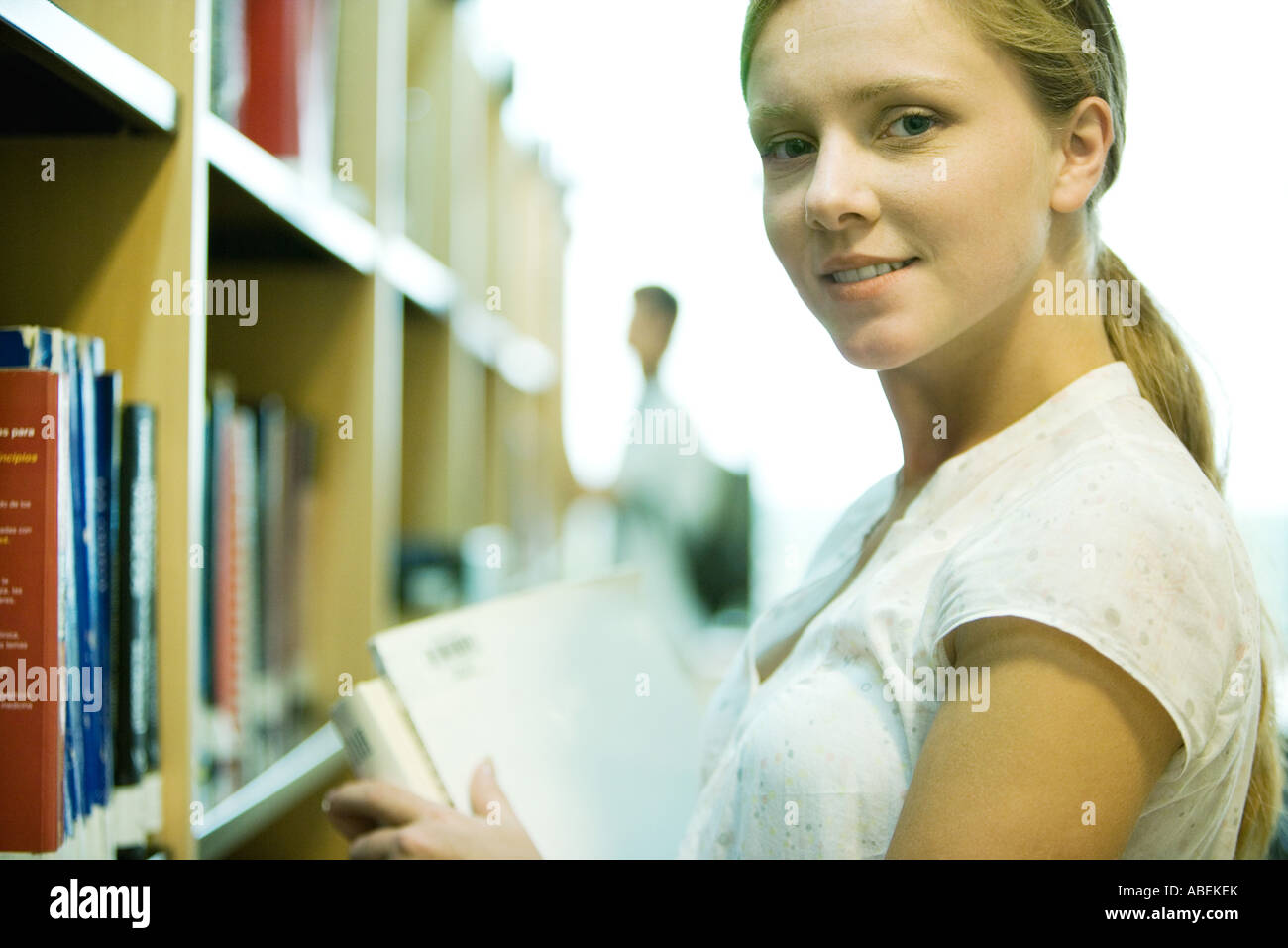 Female college student standing by shelves in library Stock Photo - Alamy