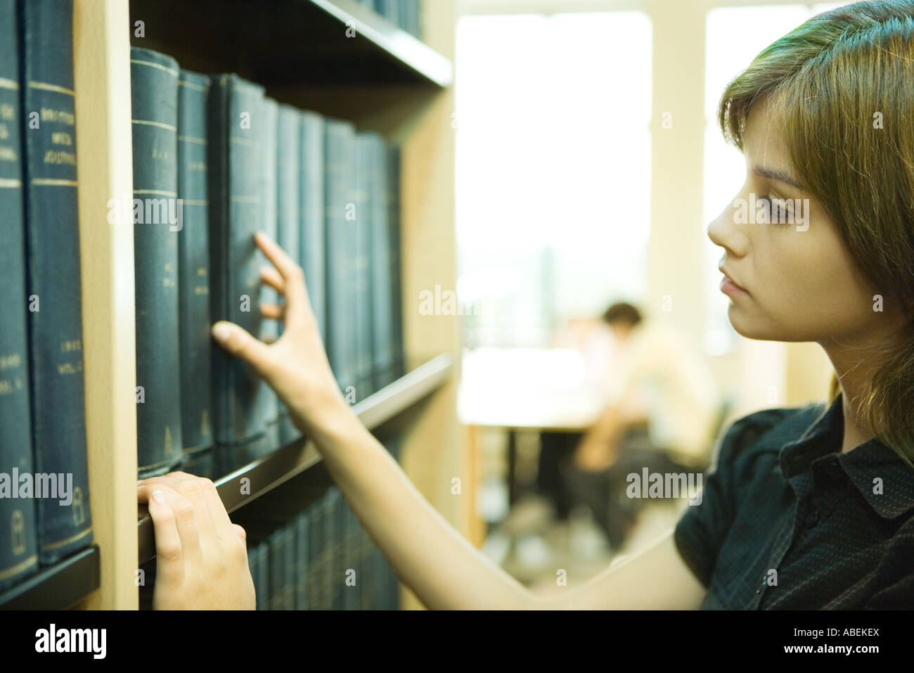 Female college student taking book from shelf in library Stock Photo ...