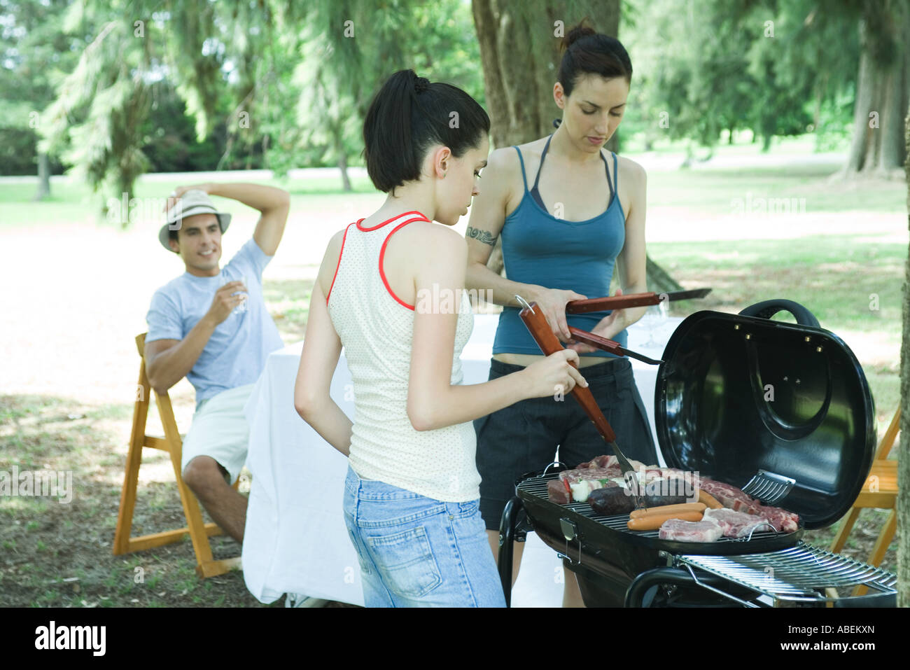 Family grilling meat on barbecue Stock Photo - Alamy