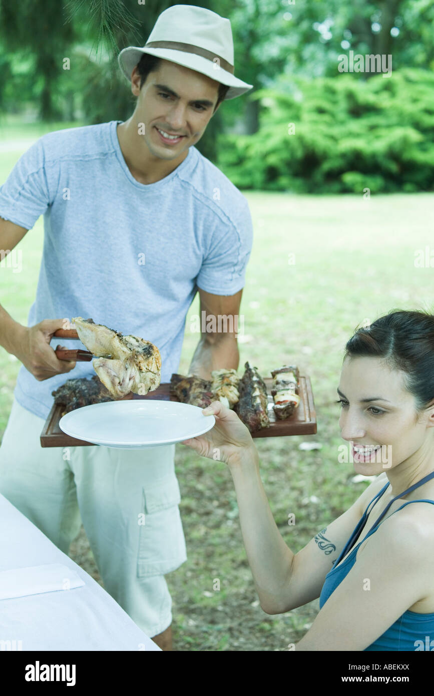 Man serving woman grilled meat during cookout Stock Photo - Alamy