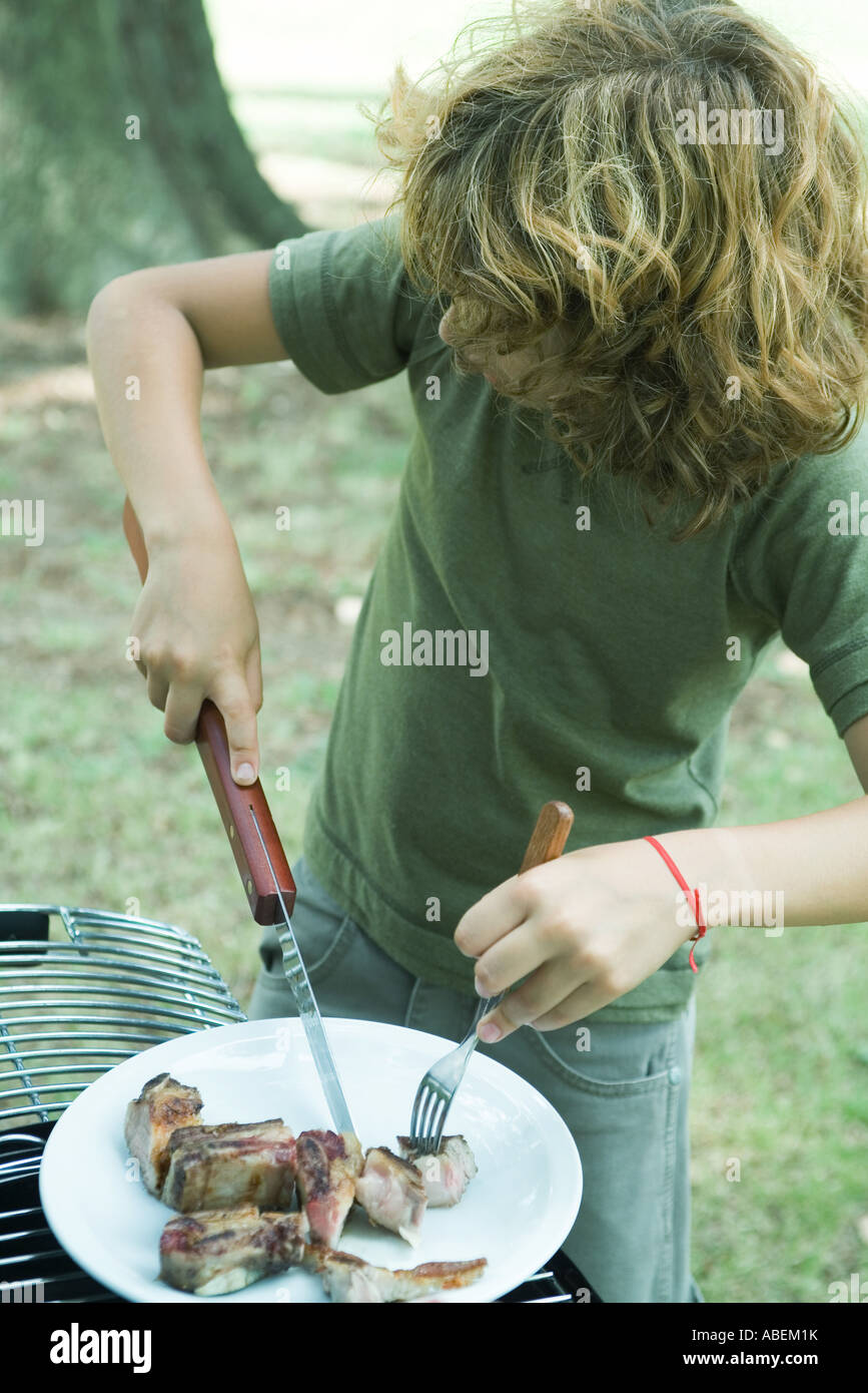 Boy cutting up meat on plate Stock Photo - Alamy