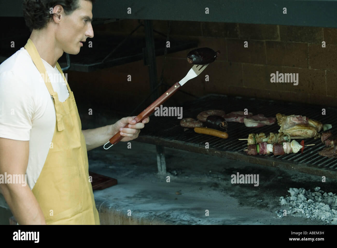 Man grilling meat on barbecue Stock Photo - Alamy