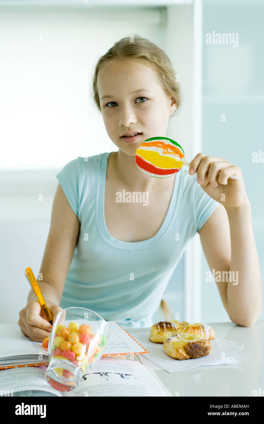 Girl eating sweets and doing homework Stock Photo - Alamy