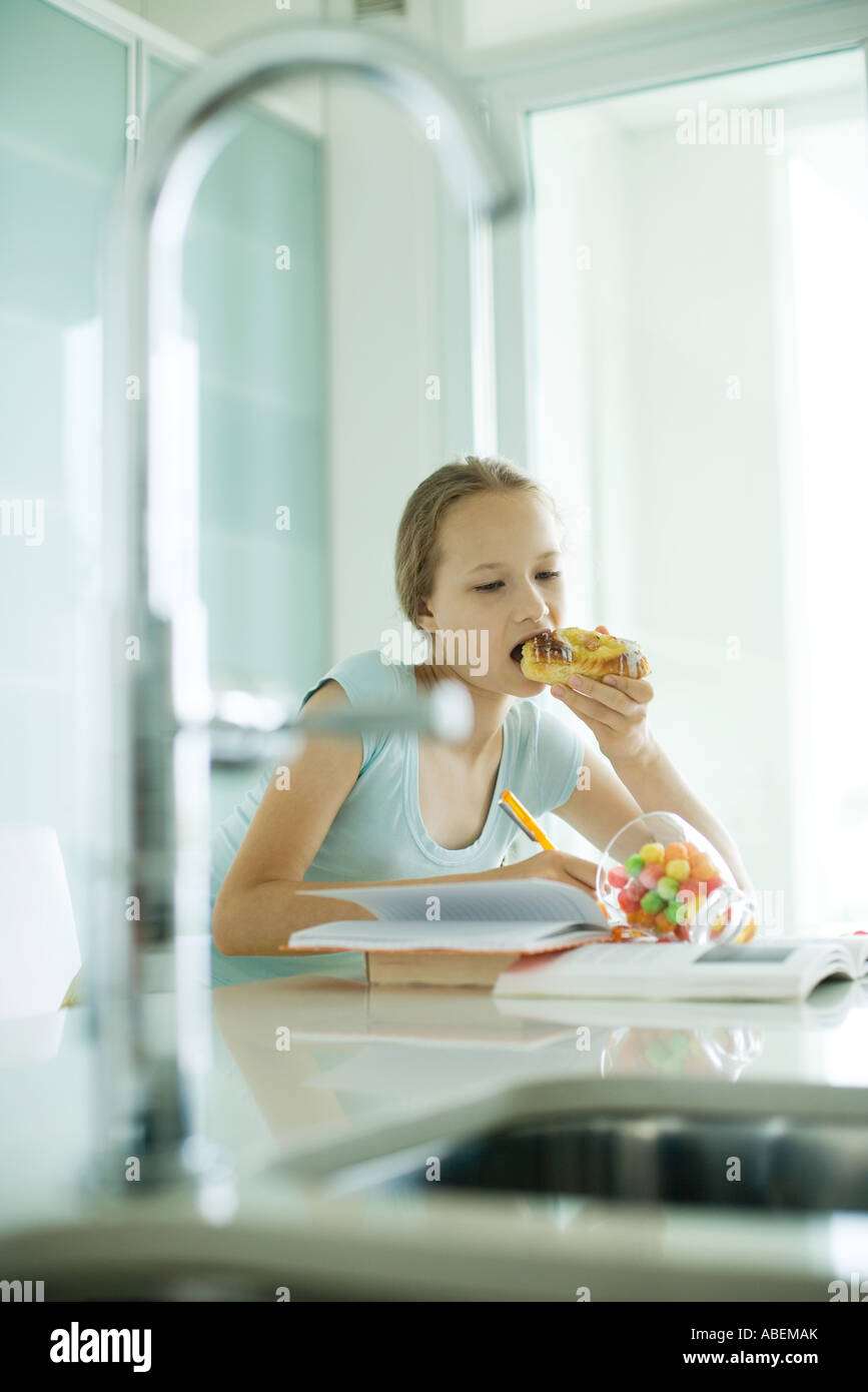 Girl eating sweets and doing homework Stock Photo - Alamy