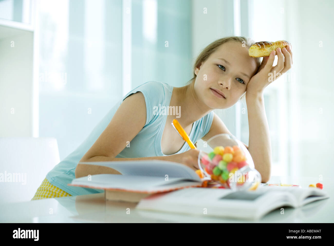 Girl eating sweets and doing homework Stock Photo - Alamy