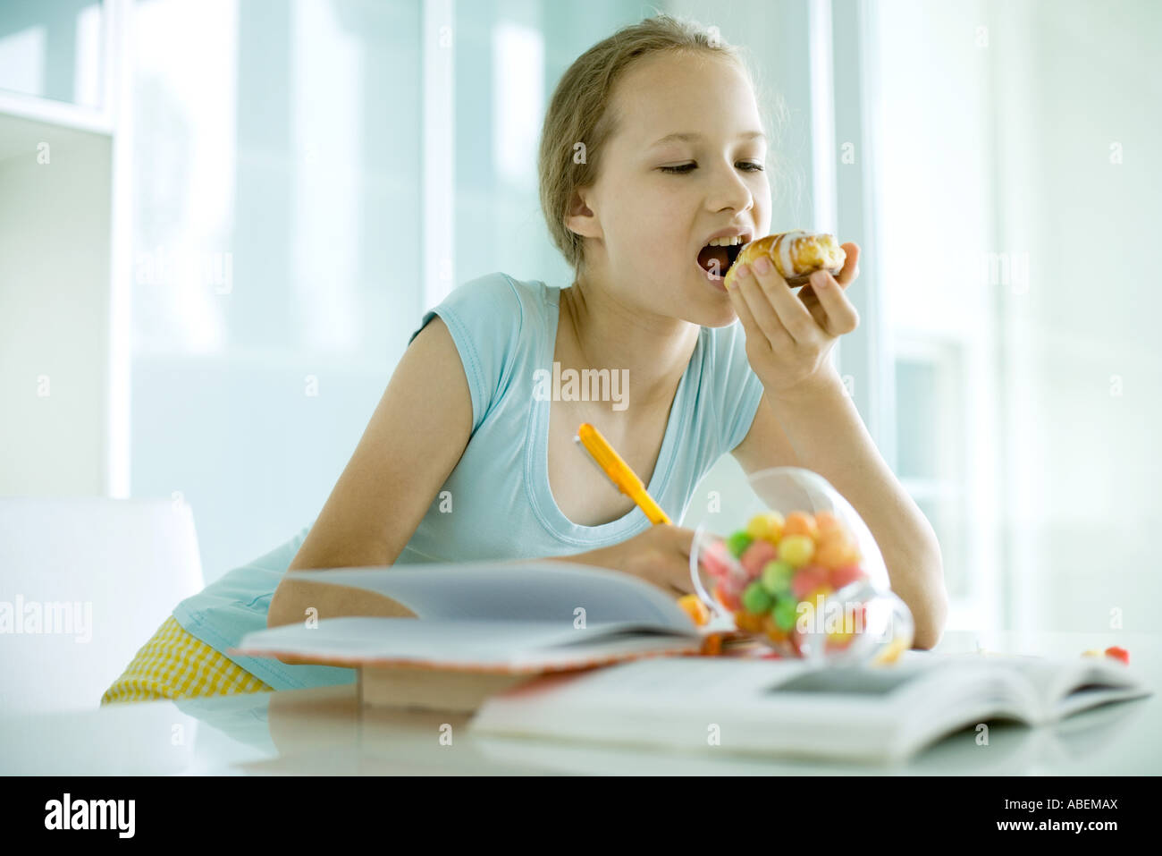 Girl eating sweet snacks and doing homework Stock Photo - Alamy